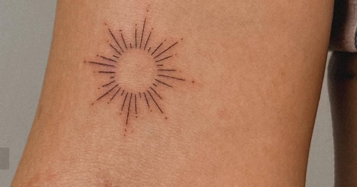 Fine line style sun tattoo located on the bicep.
