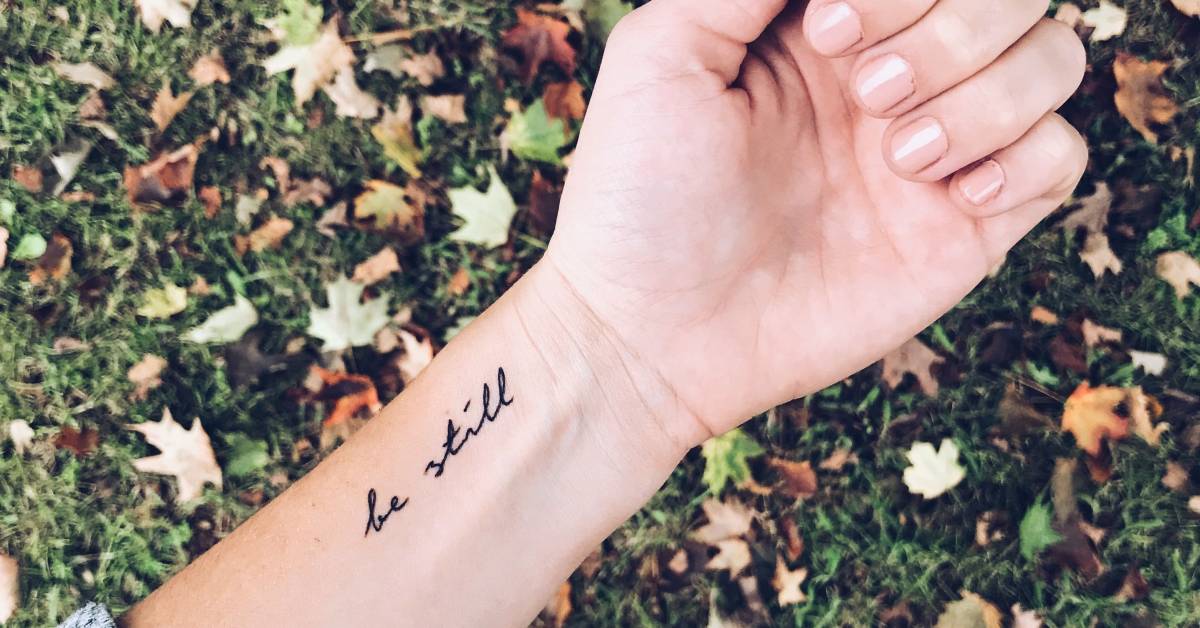 Handwritten font "be still" lettering tattoo placed on