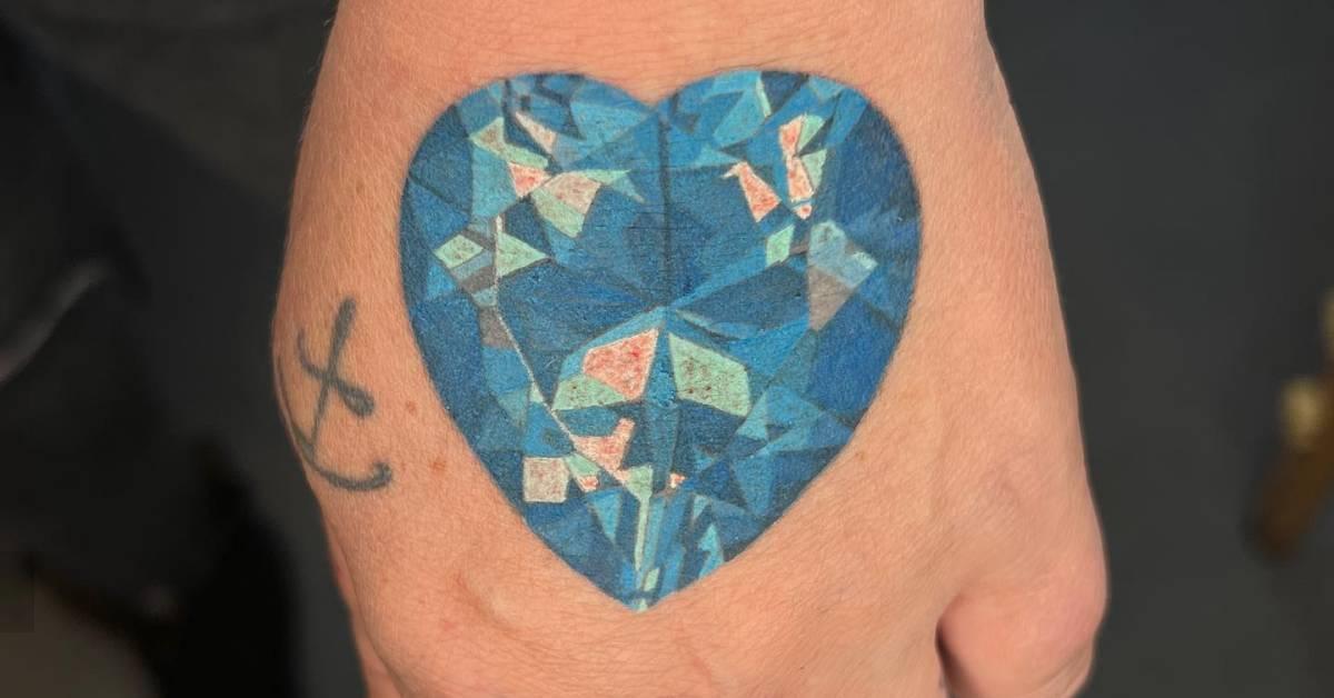 Illustrative style sapphire heart tattoo placed on the