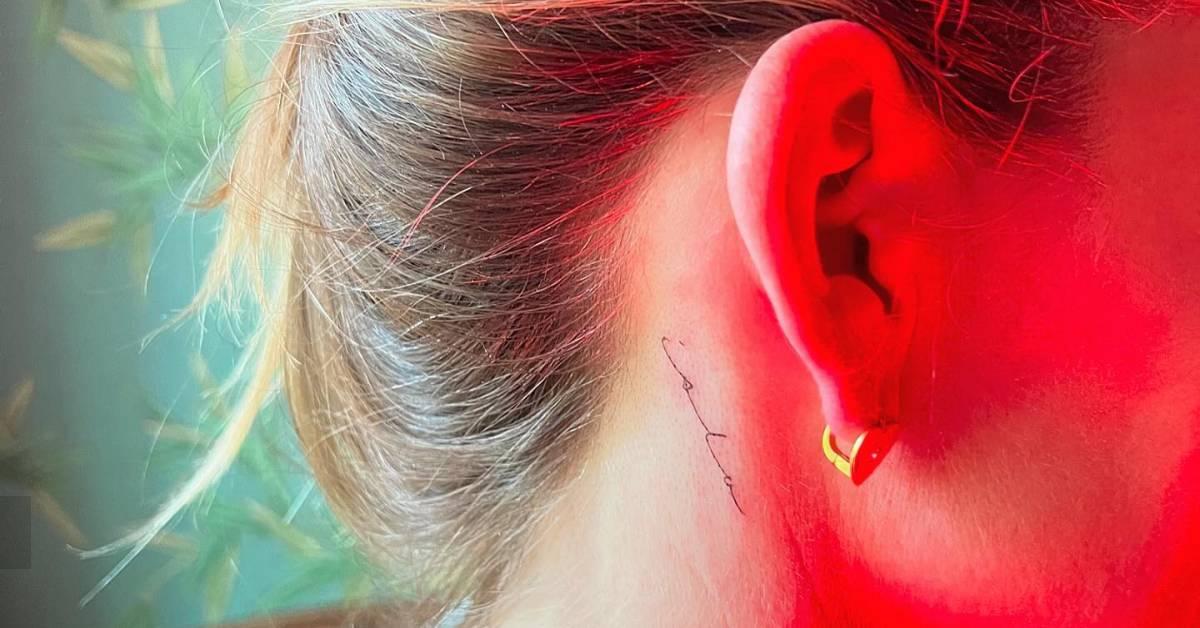 "Isla" handwritten lettering tattoo placed behind the