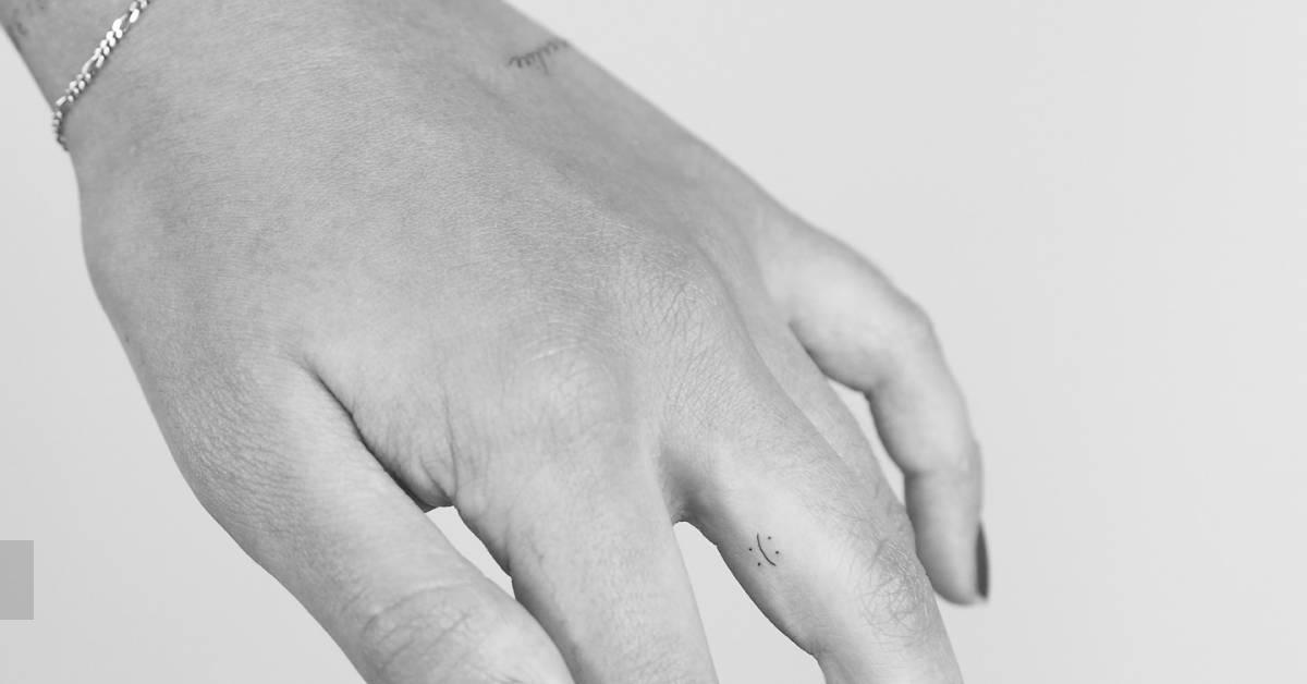 Micro happy sad face tattoo in minimalistic style done
