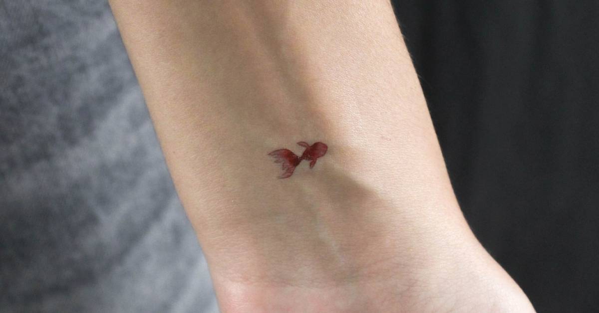 Tiny red fish temporary tattoo placed on the wrist.