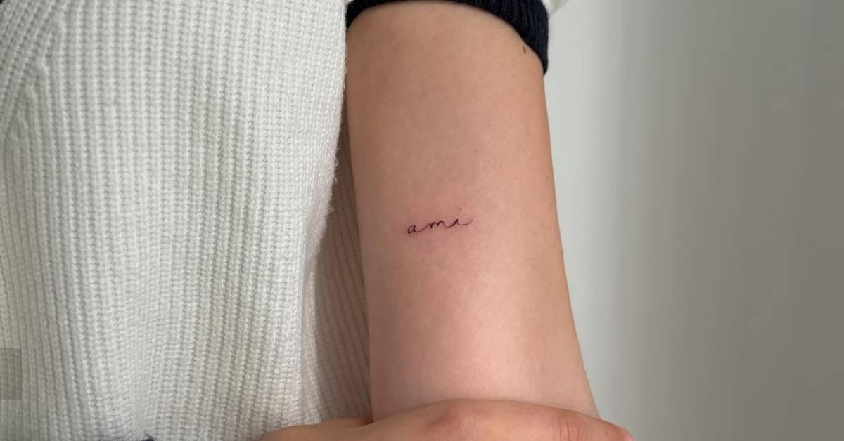 Handwritten lettering tattoo of the word "ami" located