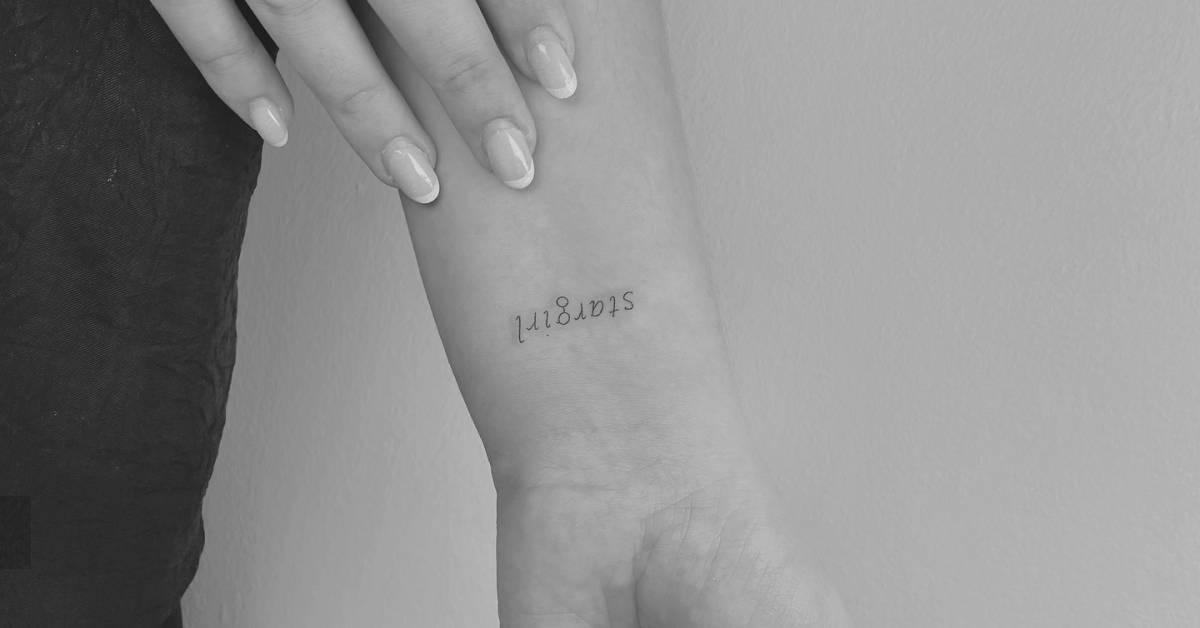Word "stargirl" lettering tattoo located on the wrist.