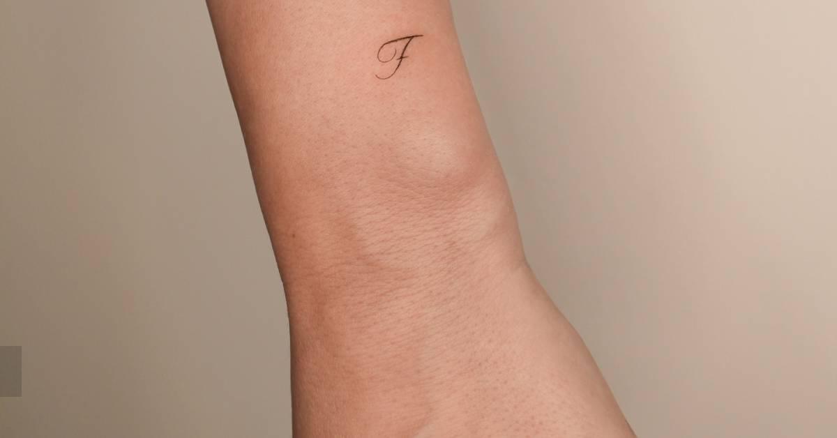 Tiny letter "F" tattoo placed on the wrist.