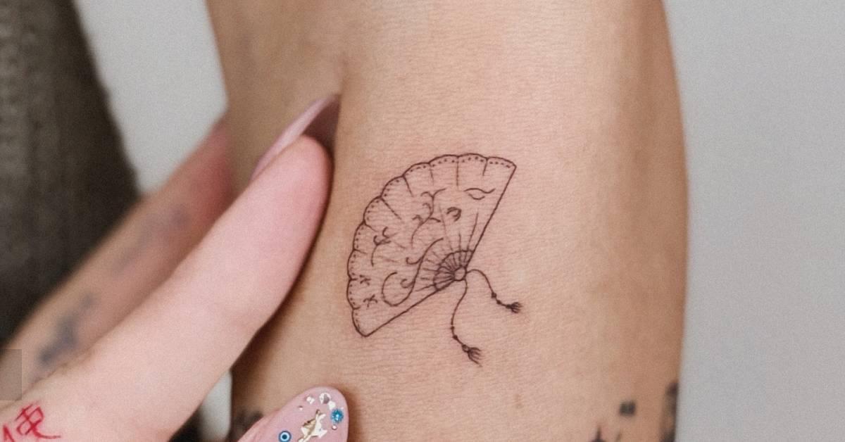 Hand fan tattoo in fine line style done on the forearm.