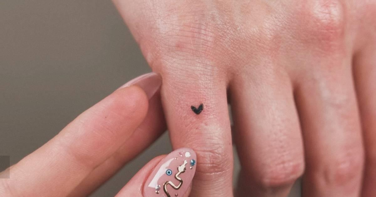 Tiny minimalistic heart tattoo located on the finger.
