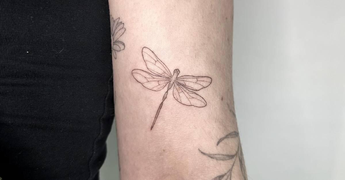 Dragonfly tattoo in fine line style placed on the