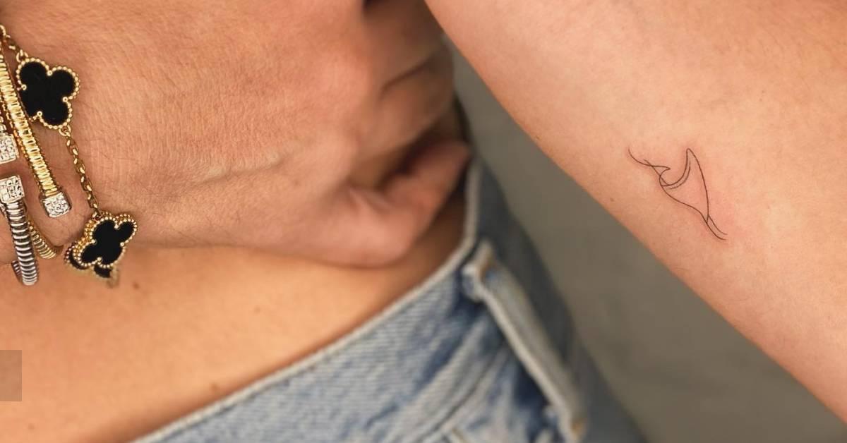 Fine line style shark fin tattoo located on the inner