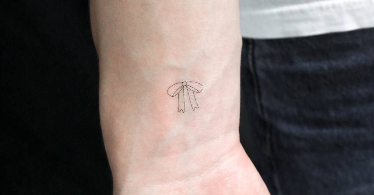 Small fine line bow temporary tattoo located on the