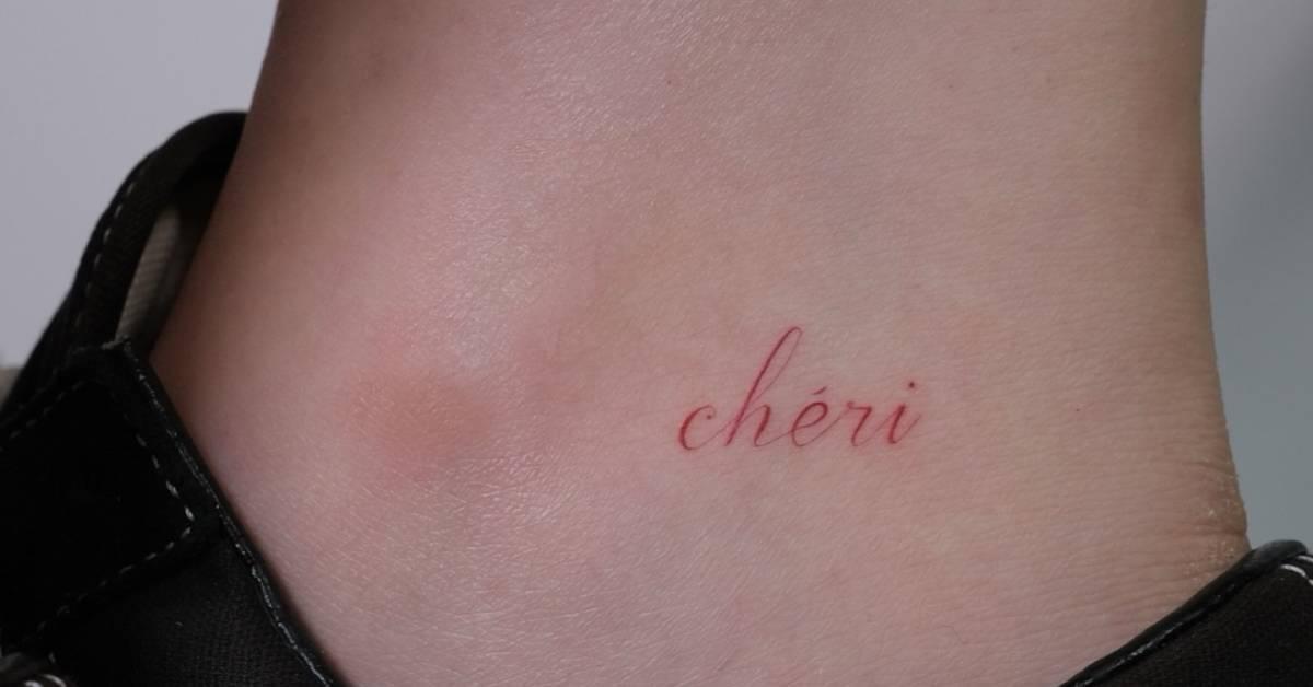 "Chéri" lettering tattoo in red ink placed on the