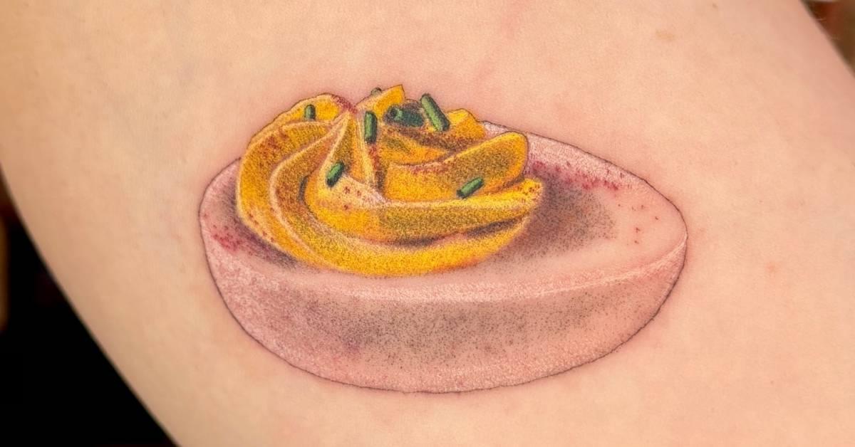 Deviled egg tattoo located on the inner arm.