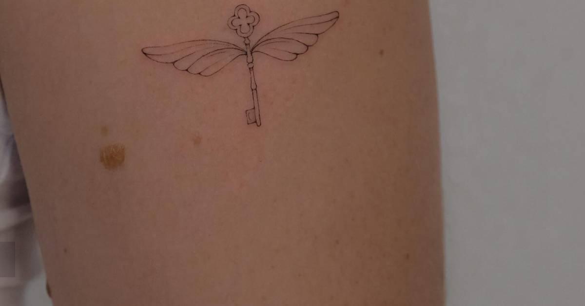 Fine line style Winged Key tattoo located on the upper