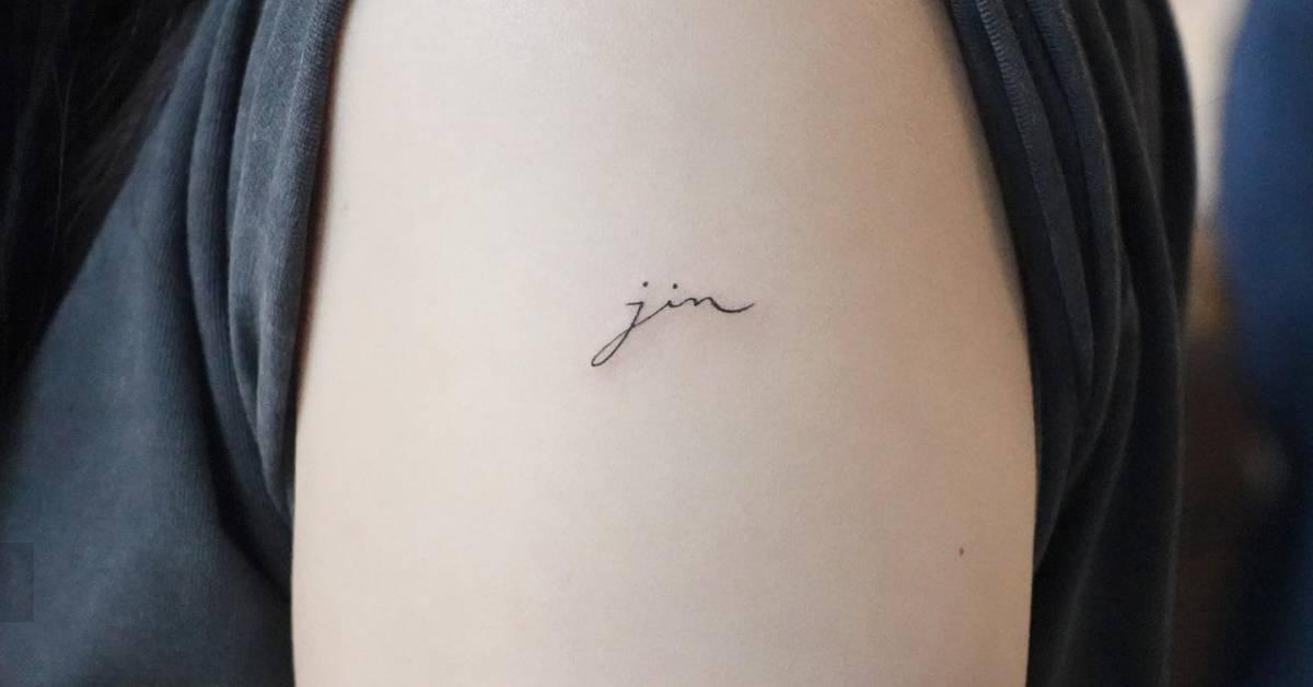 Handwritten name "Jin" tattoo located on the upper arm.