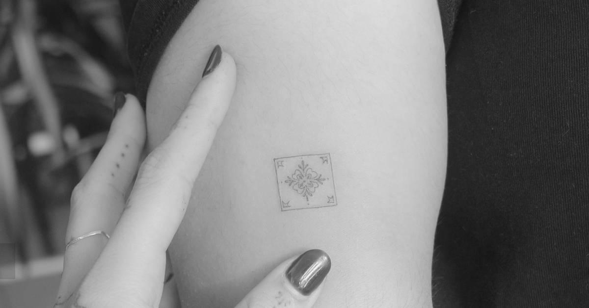 Fine line style tile tattoo placed on the upper arm.