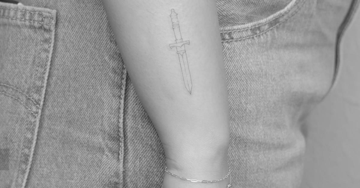 Little fine line style dagger tattoo located on the
