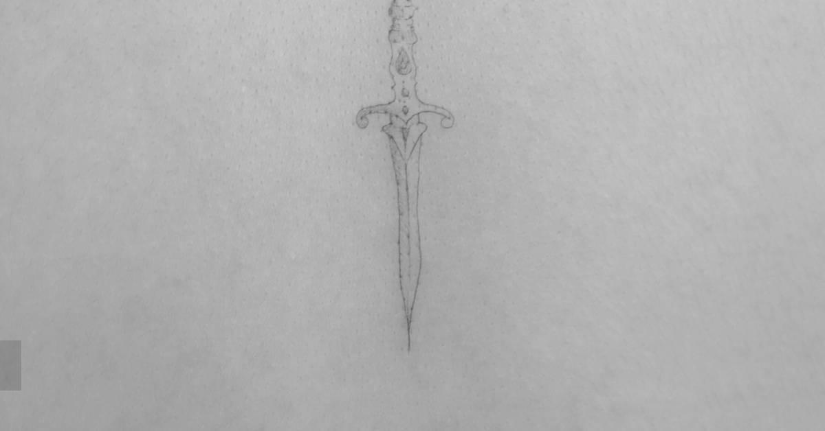 Fine line style dagger tattoo located on the back.
