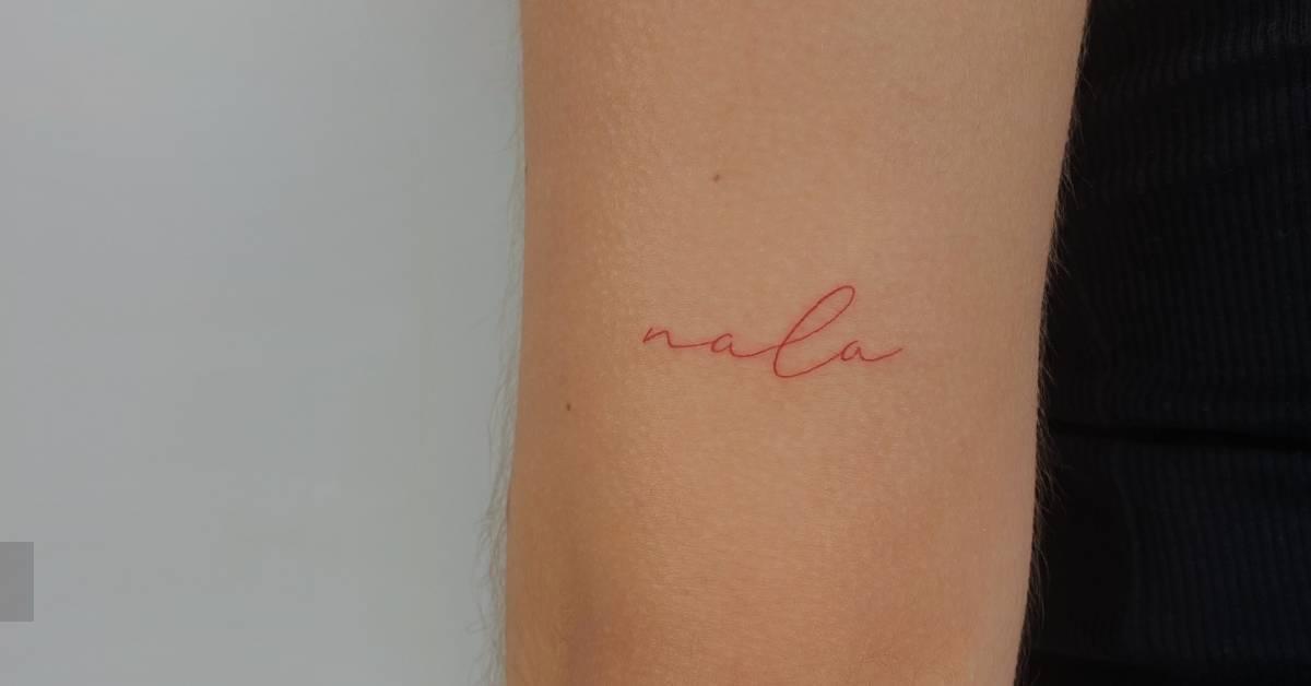 "Nala" Handwritten lettering tattoo in red ink located
