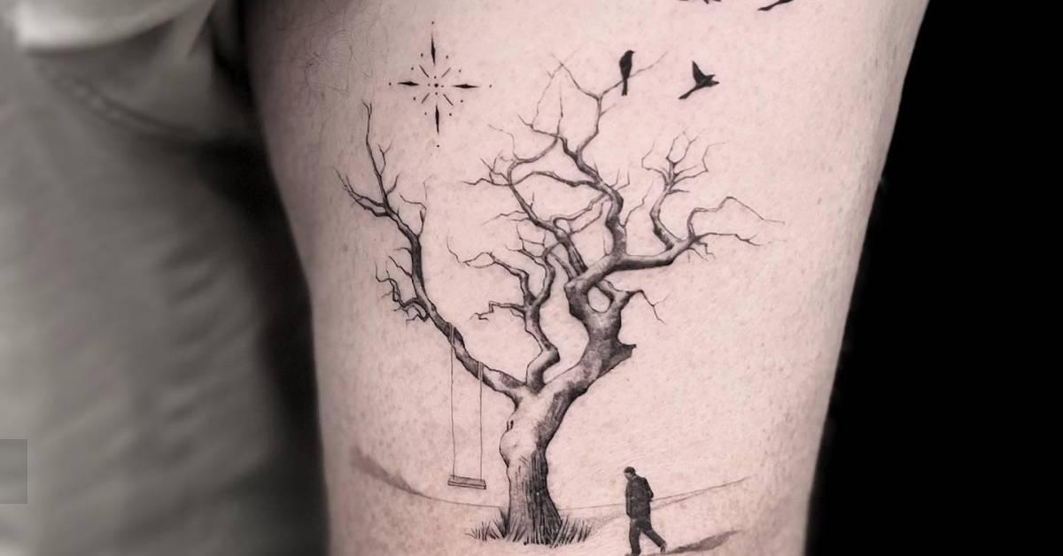 Leafless tree and swing tattoo located on the thigh,