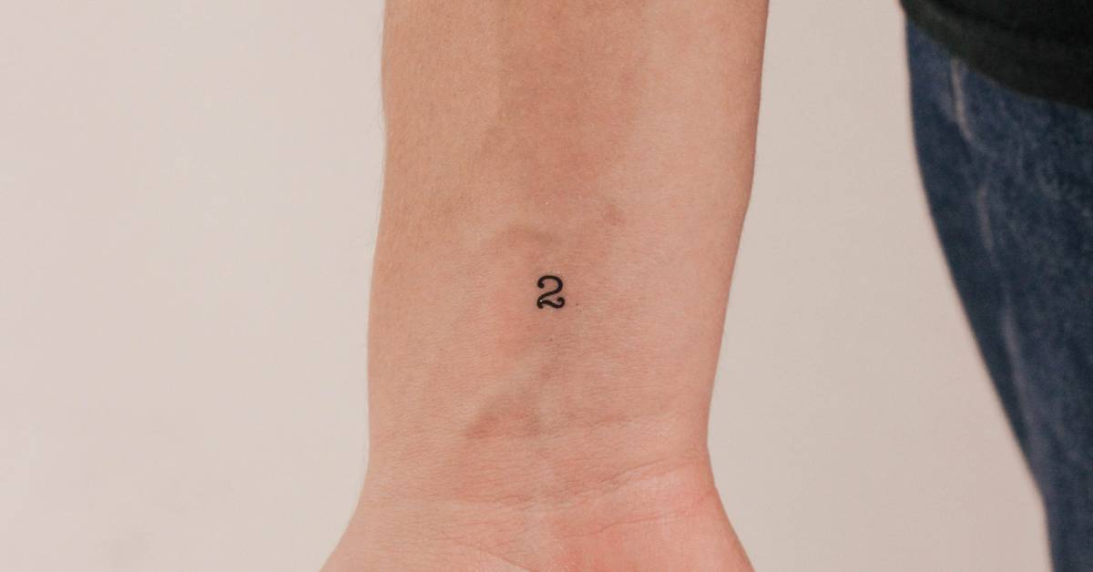 Tiny number "2" temporary tattoo located on the wrist.