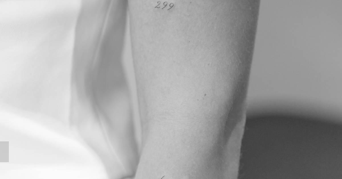 Number "299" and "dare to" tattoos located on the arm.