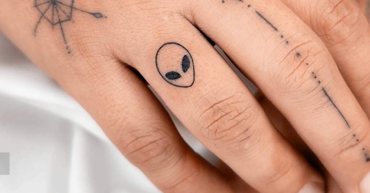 Little alien head tattoo in minimalistic style placed