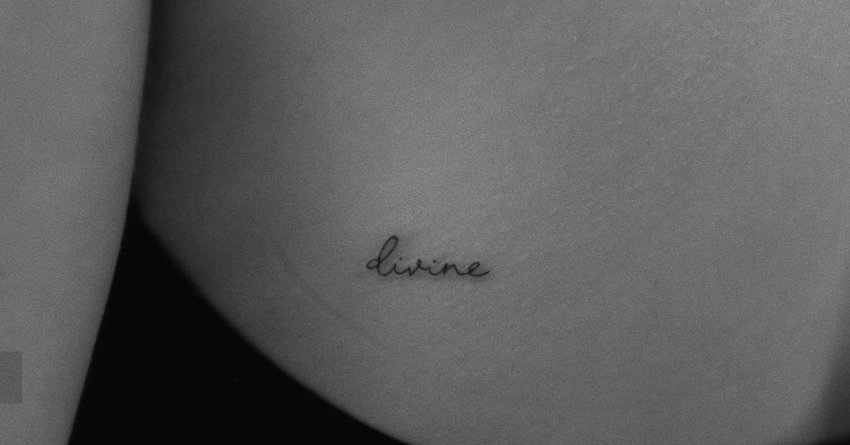 Tattoo of the word "divine" handwritten on the back.