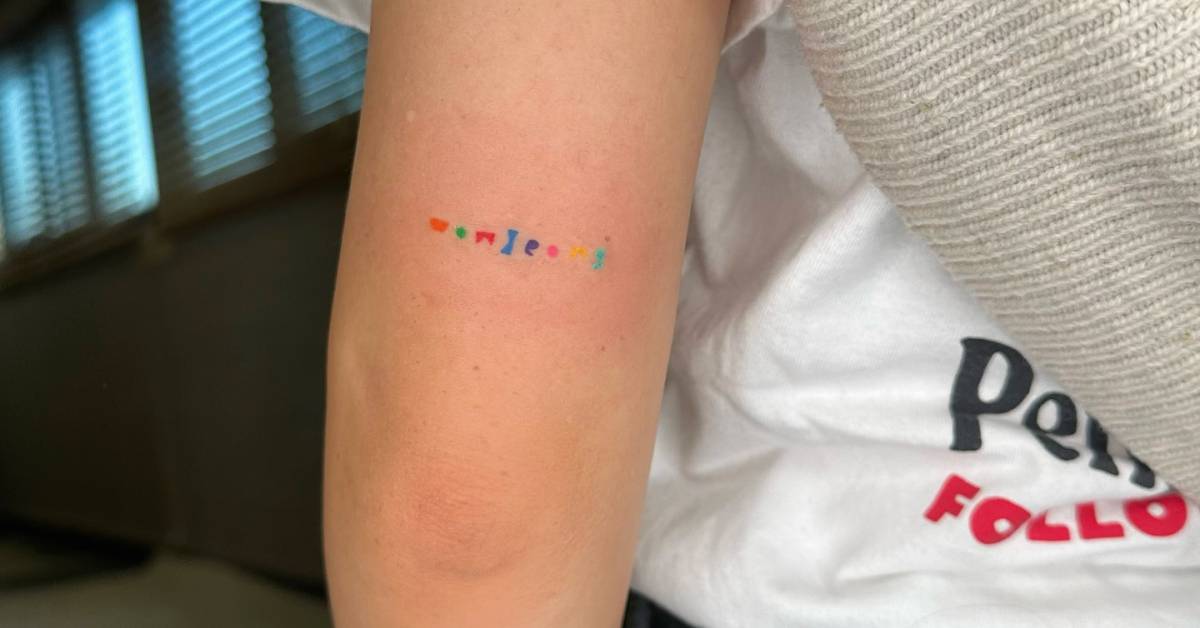 Hand poked colorful lettering tattoo done on the