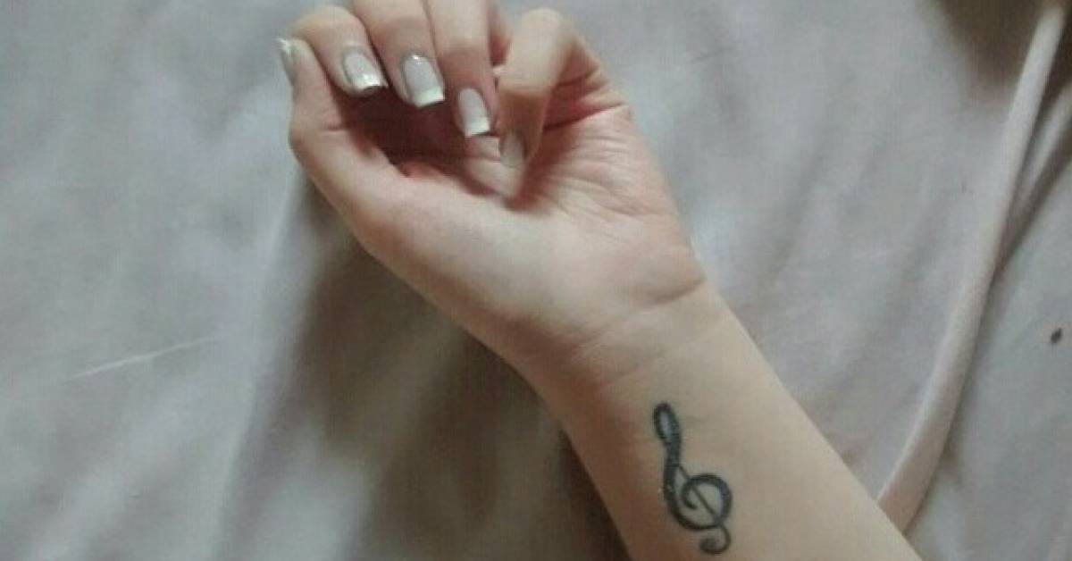 Treble clef tattoo on the left wrist.