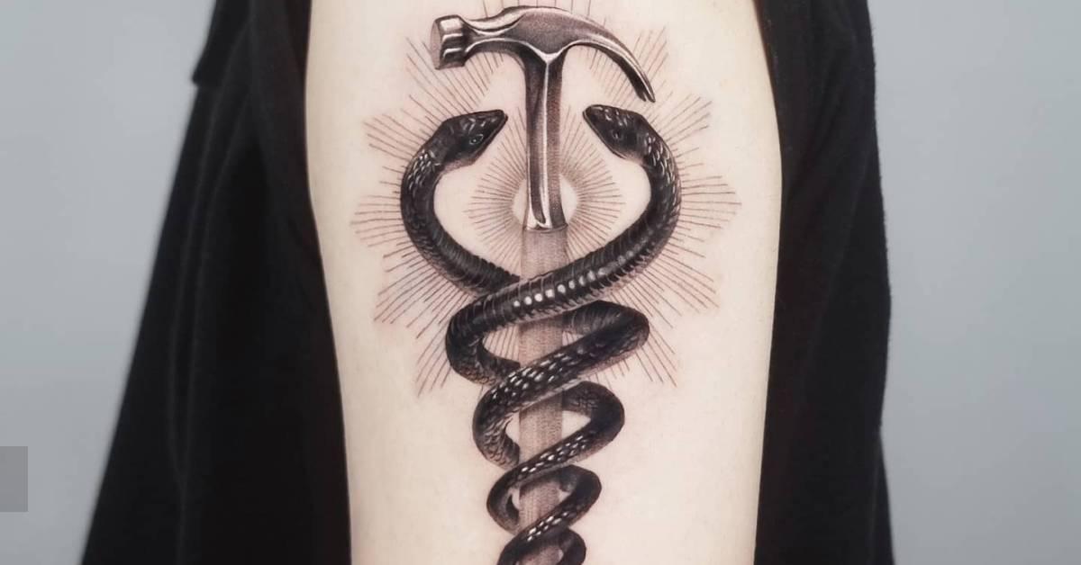 Caduceus with hammer tattooed on the upper arm, black