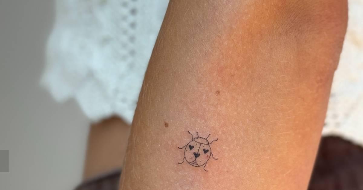 Tiny fine line ladybug tattoo located on the upper arm.