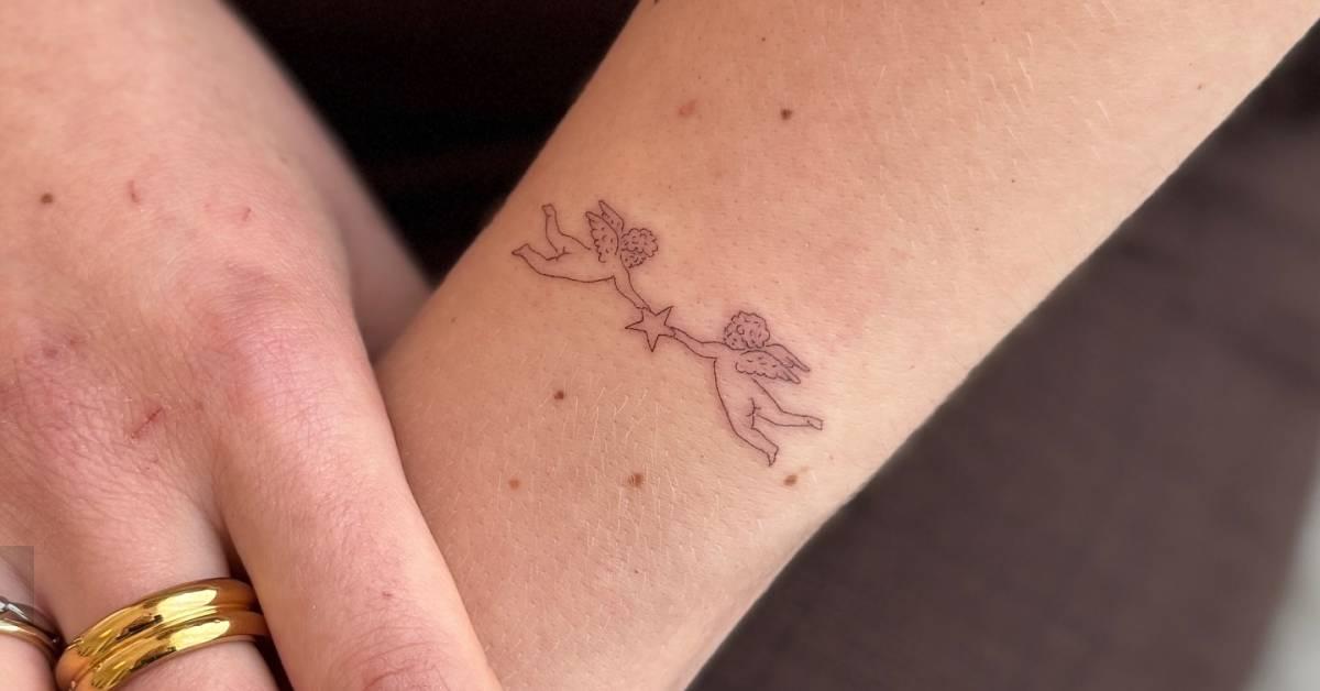 Fine line style minimalist cherubs tattoo located on