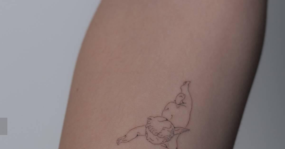 Fine line style cherub tattoo located on the inner