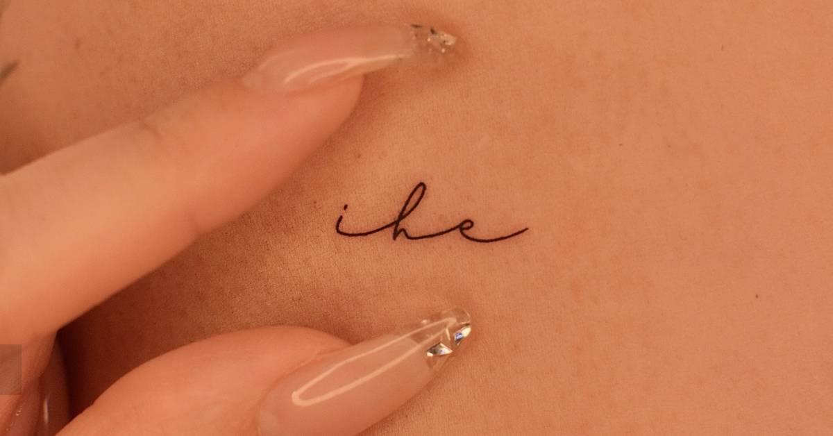 Tiny handwritten initials tattoo located on the back.