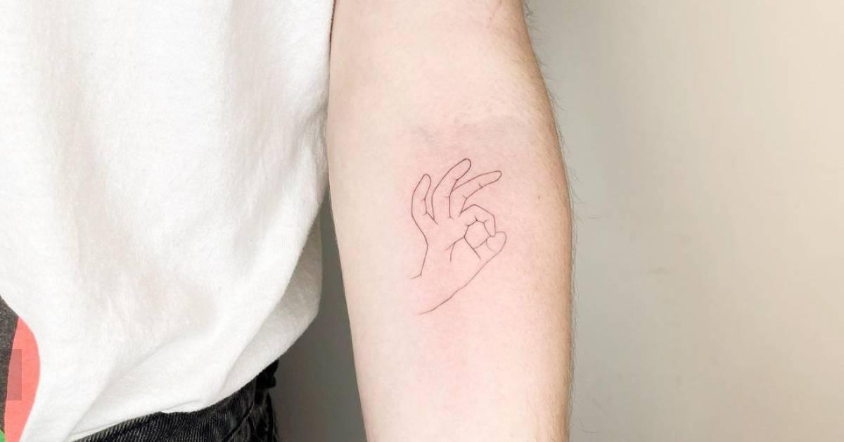 OK gesture tattoo located on the inner forearm.