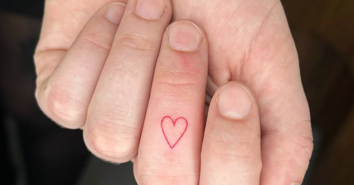 Minimalistic red heart tattoo hand poked on the finger.