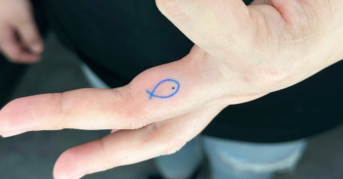 Tiny minimalistic blue fish tattoo hand poked on the