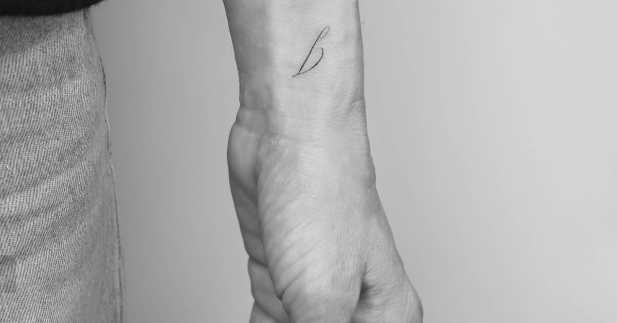 Script font letter "J" tattoo located on the wrist.