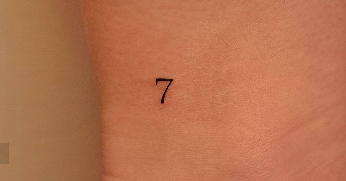 Tiny minimalistic number "7" tattoo located on the
