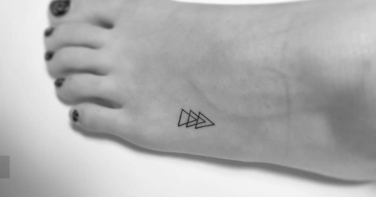 Fine line style triangles tattooed on the foot.