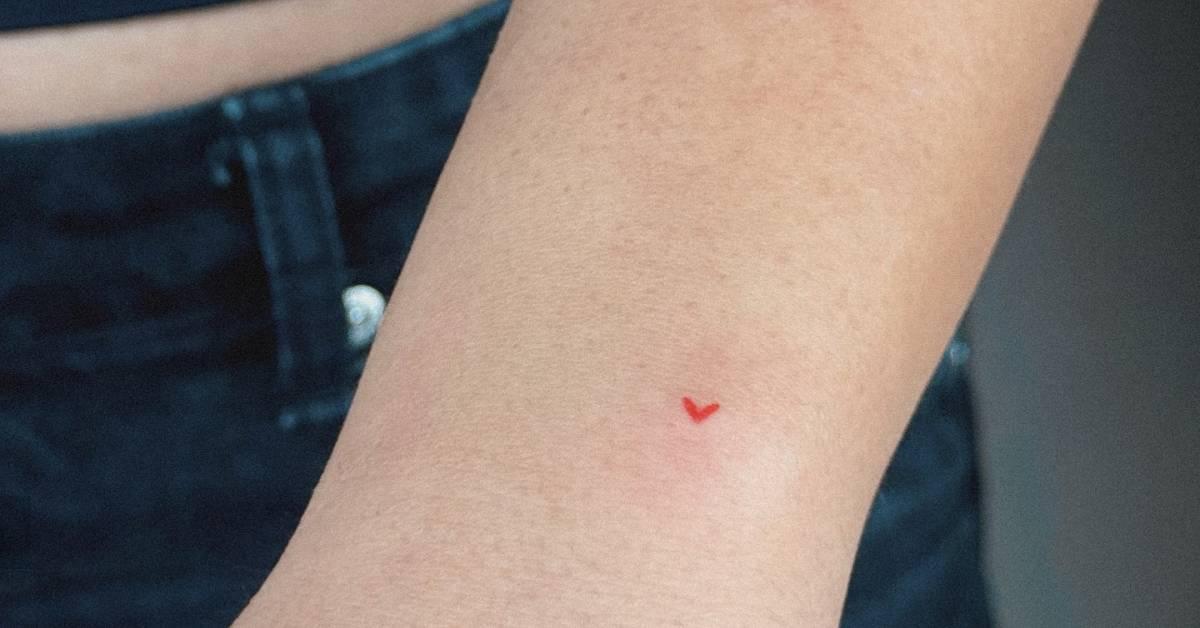 Tiny red heart tattoo located on the wrist, done in