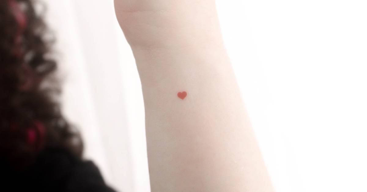 Tiny red heart temporary tattoo located on the wrist.