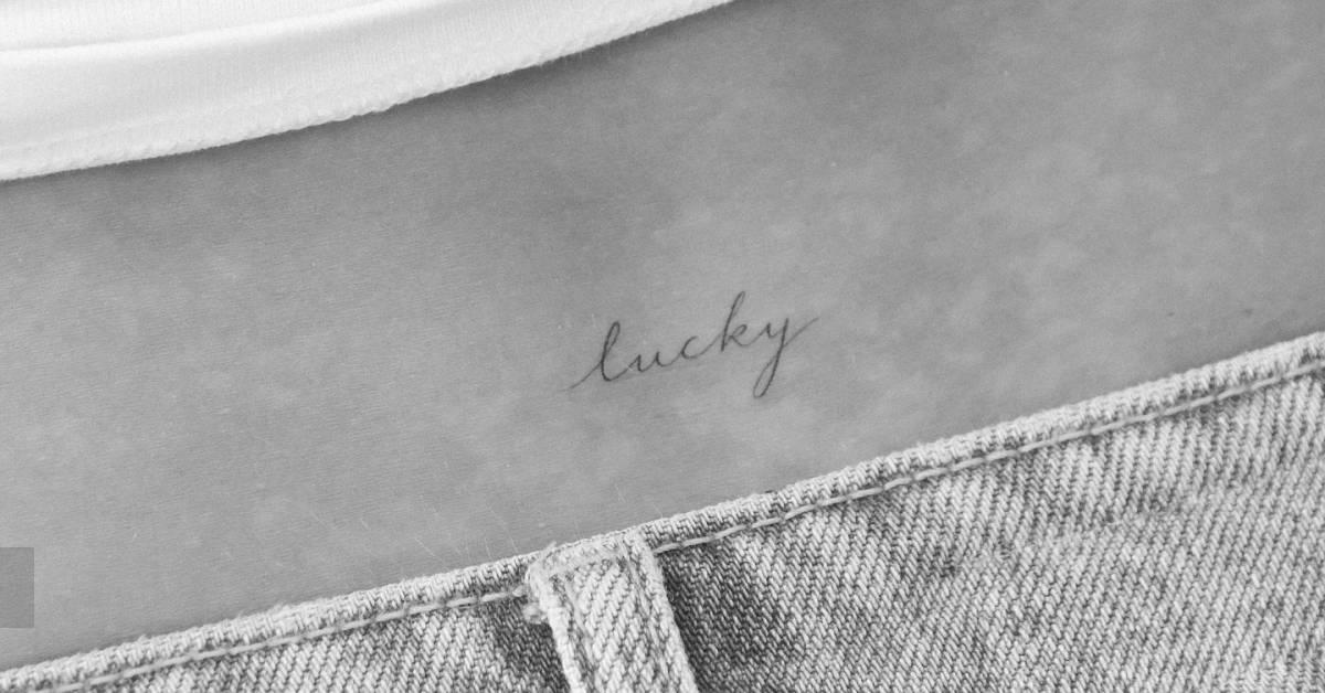 Handwritten word "lucky" lettering tattoo located on
