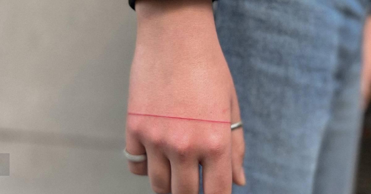 Minimalistic red line tattoo done on the hand.