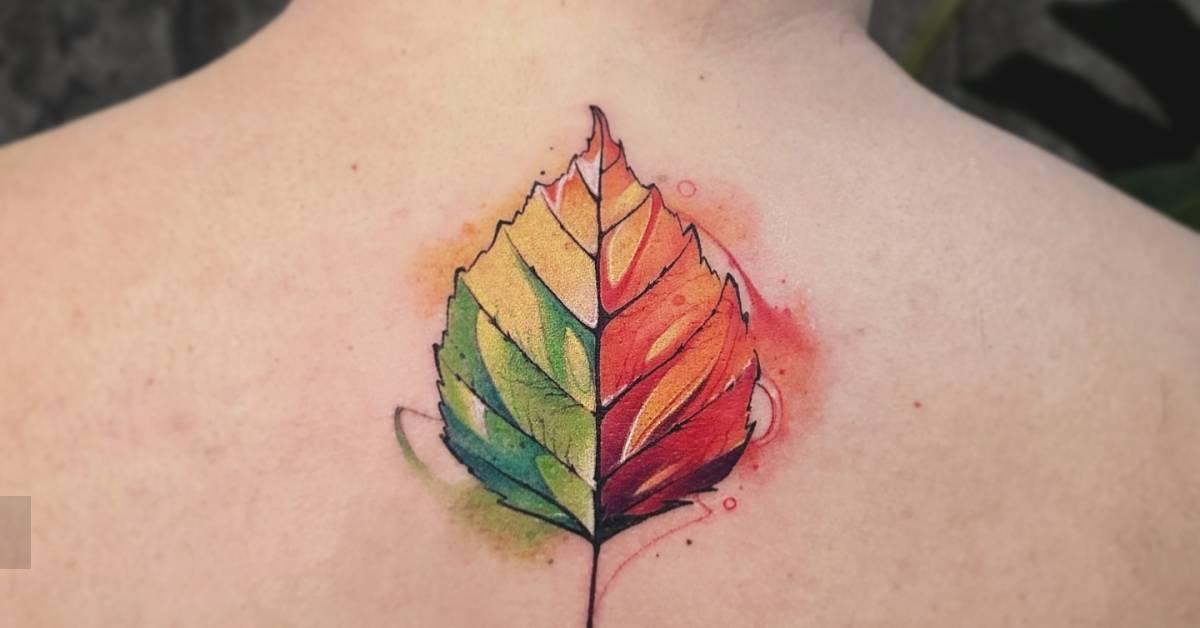 Watercolor style leaf tattoo located on the upper back.