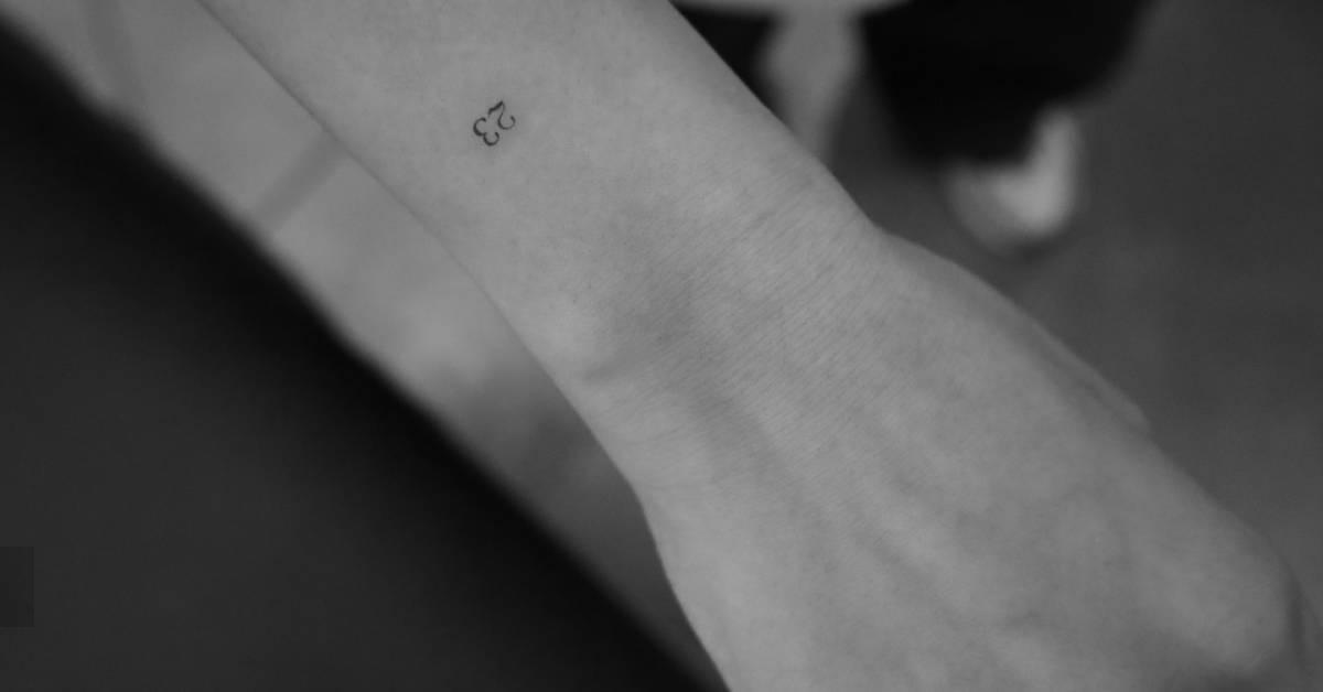 Tiny tattoo of the number "23" in serif font placed on