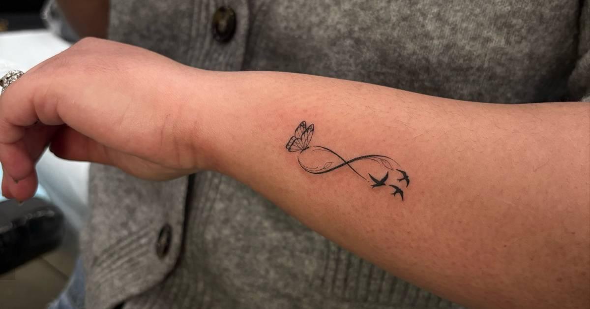 Infinity symbol, butterfly and flying birds tattoo