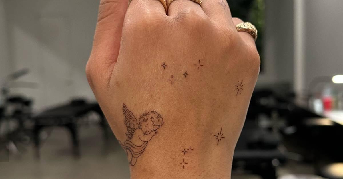 Fine line style cherub and sparkling stars tattoo