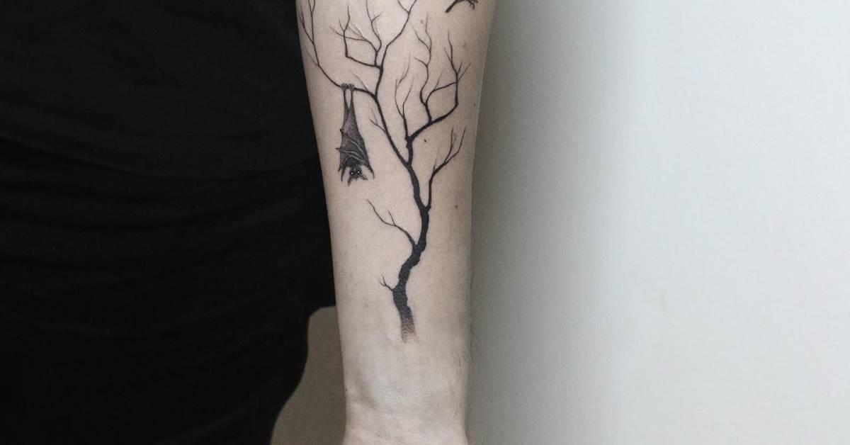 Bat and leafless tree tattoo located on the inner