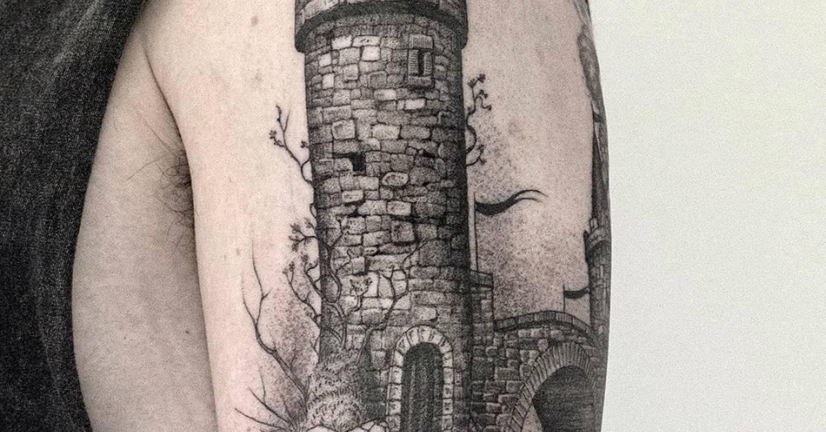 Blackwork tower tattoo located on the upper arm.